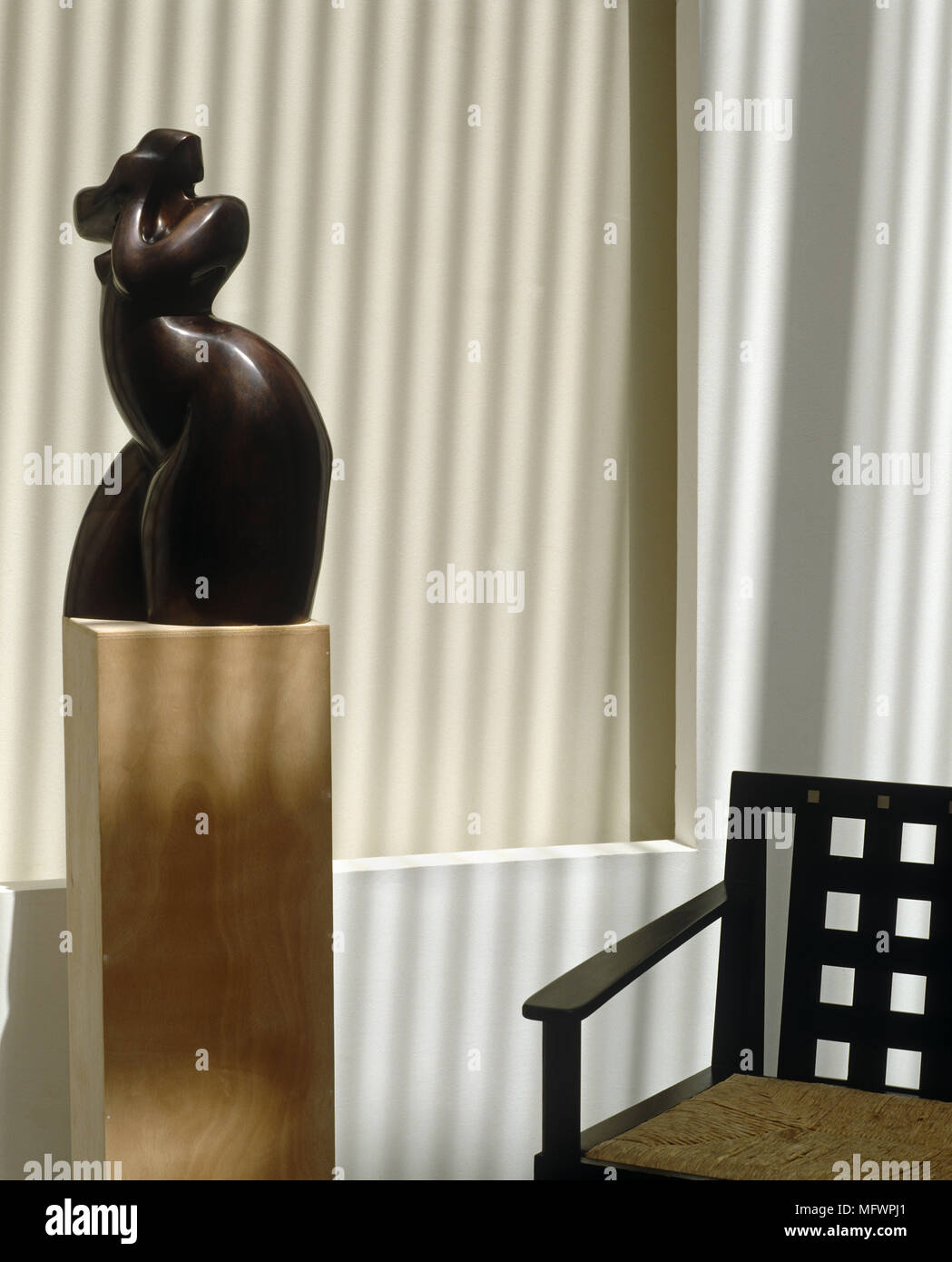 Contemporary sculpture on plinth next to chair Stock Photo - Alamy