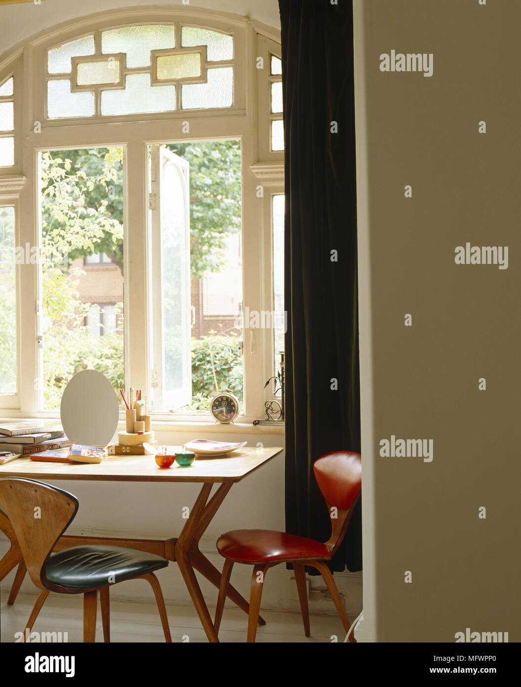 Retro style chairs and wooden table next to window with dark curtains ...