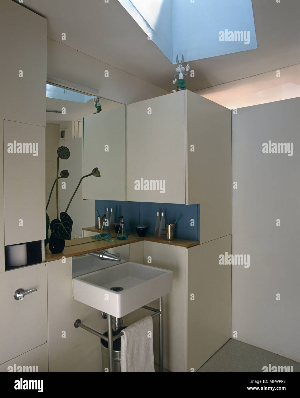 Minimalist angular bathroom with white units and rectangular washbasin ...