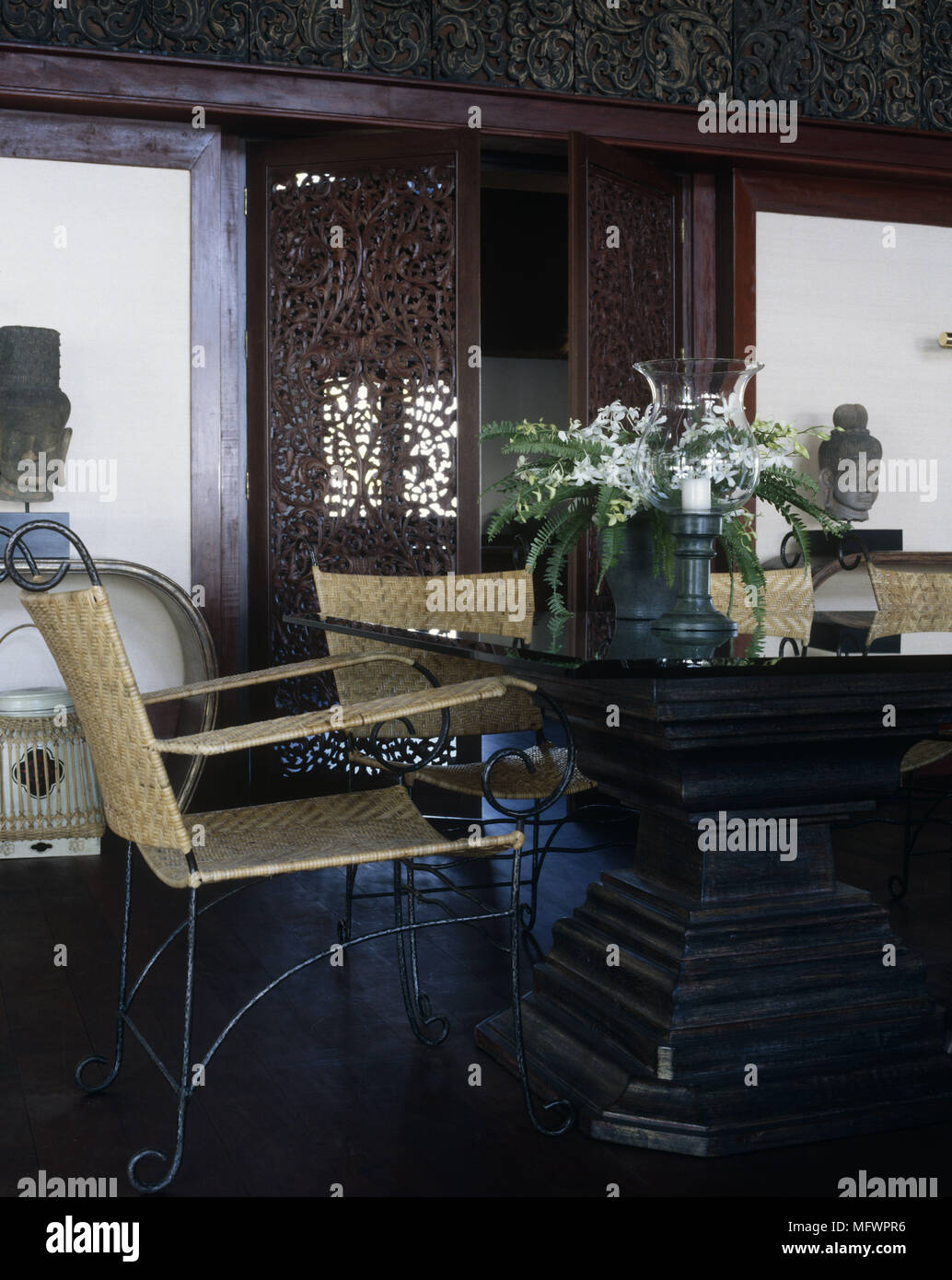 Metal and wicker chairs facing table with glass top and supports in ...