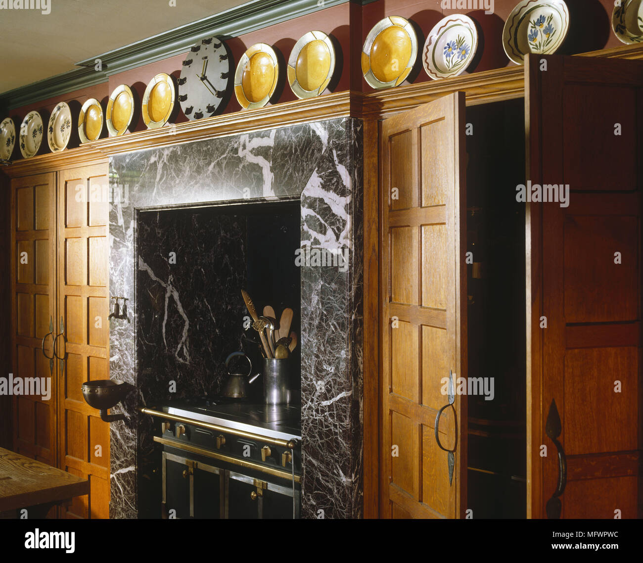 Range oven set in marble recess with row of ornamental plates above and ...