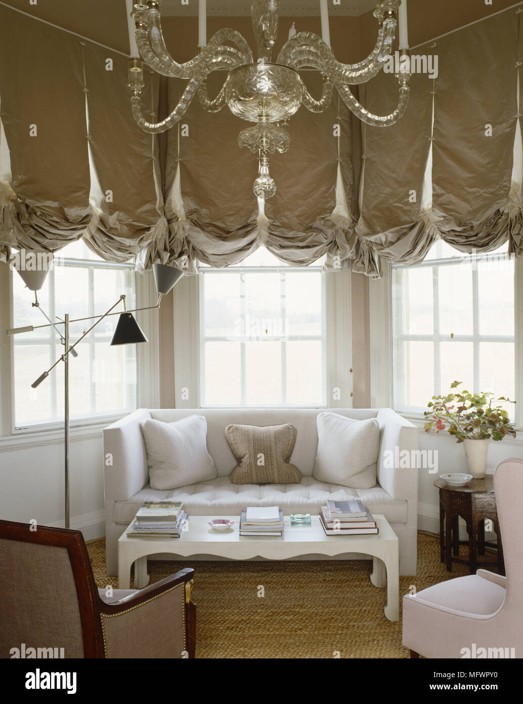 Chandelier above chairs facing coffee table and sofa next to bay ...