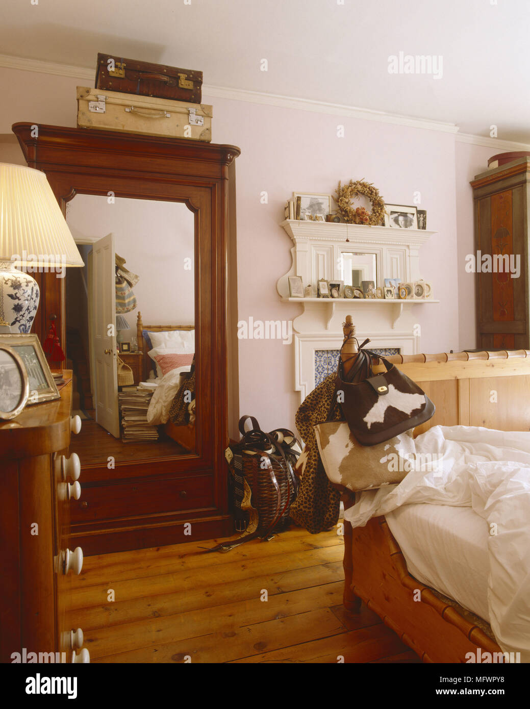 Cluttered bedroom with wooden floor and wardrobe with mirror next to ...