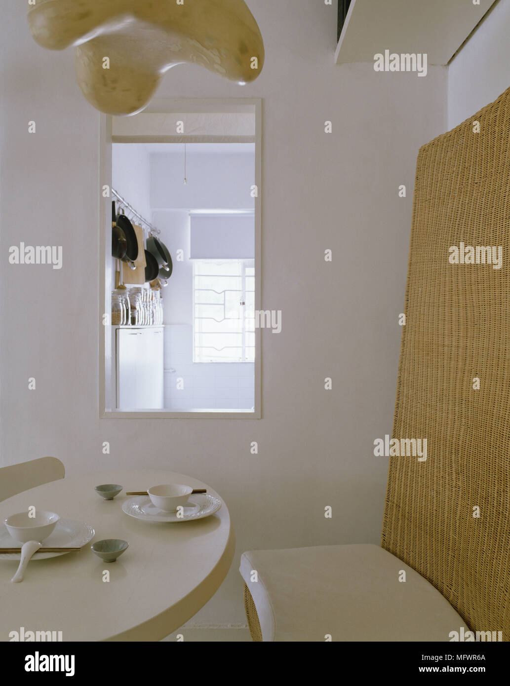 Dining room with curved table and seat with wicker back next to window ...