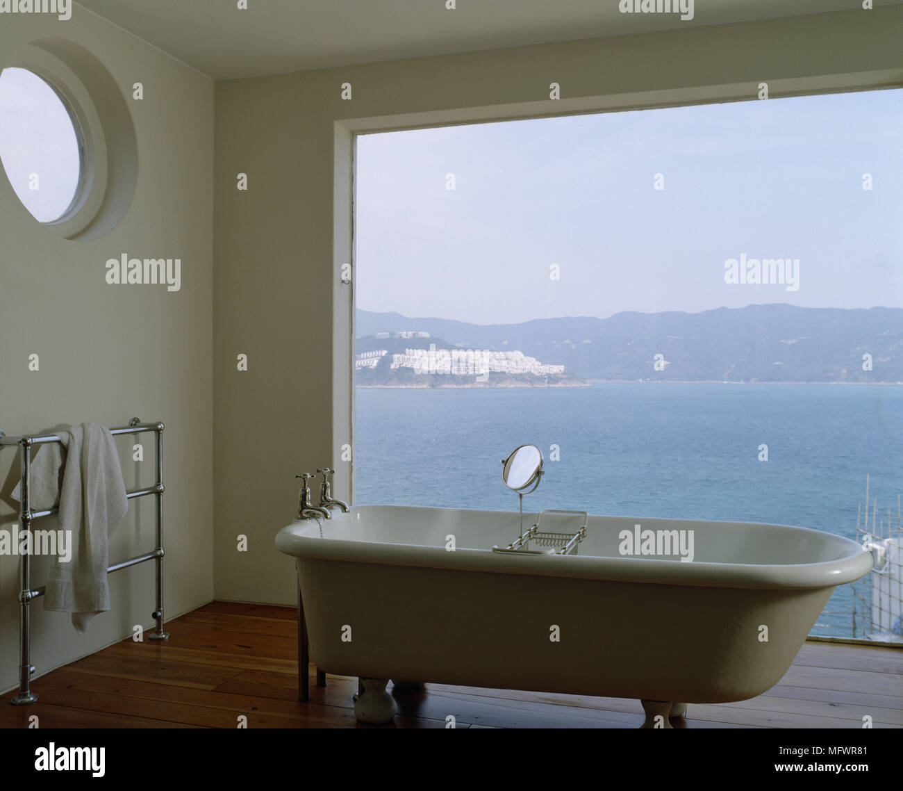 Freestanding bath in front of large window with sea view Stock Photo ...