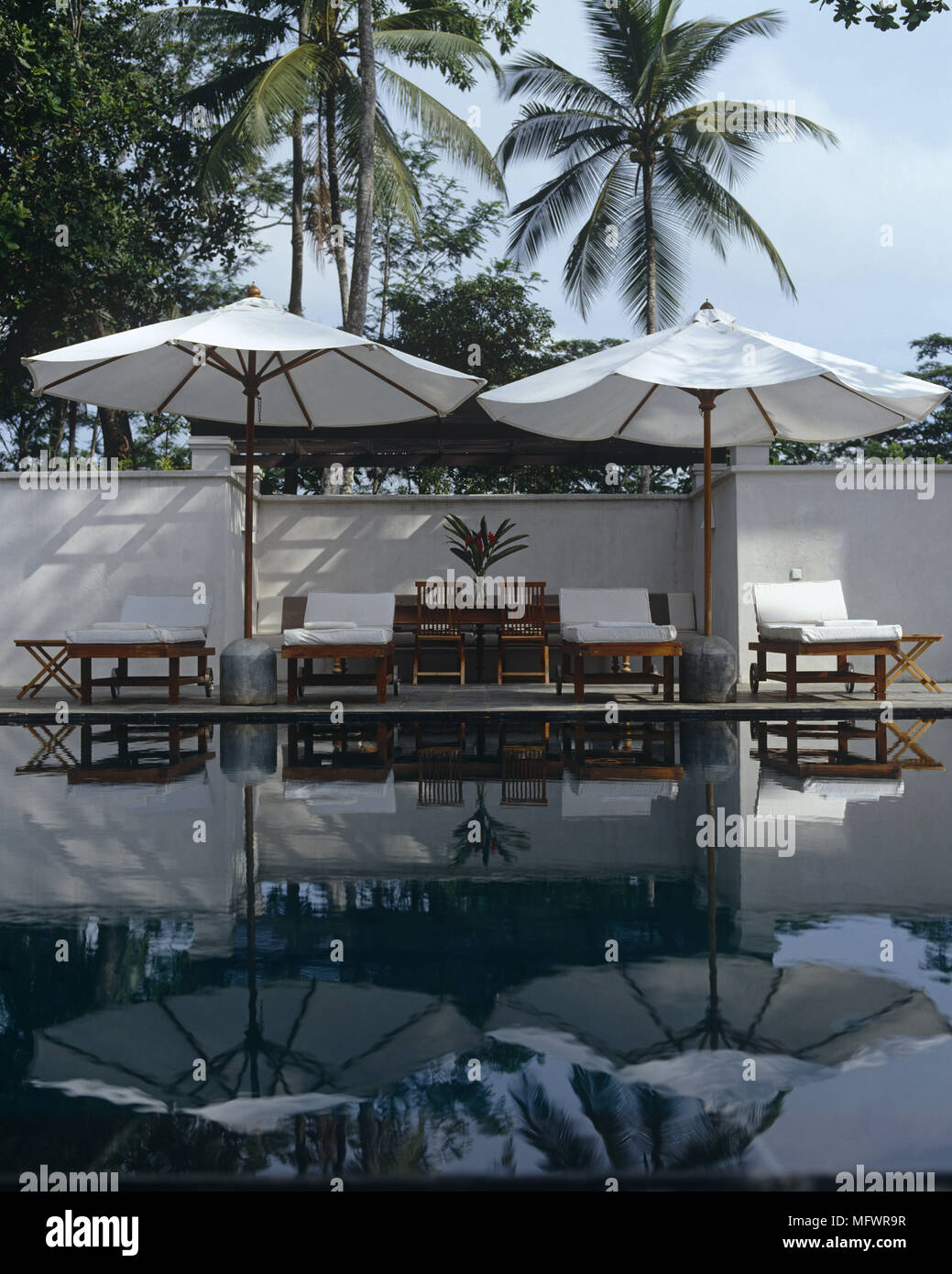 Sun loungers and parasols beside swimming pool Stock Photo - Alamy