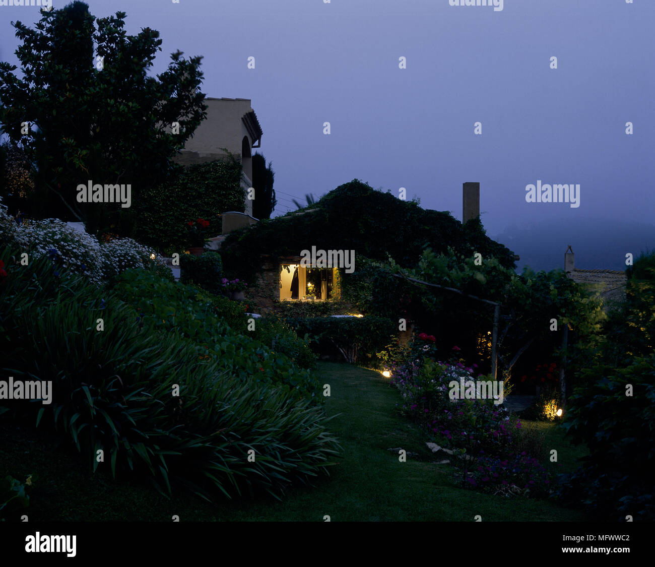 View of a lit house from a lawn Stock Photo - Alamy