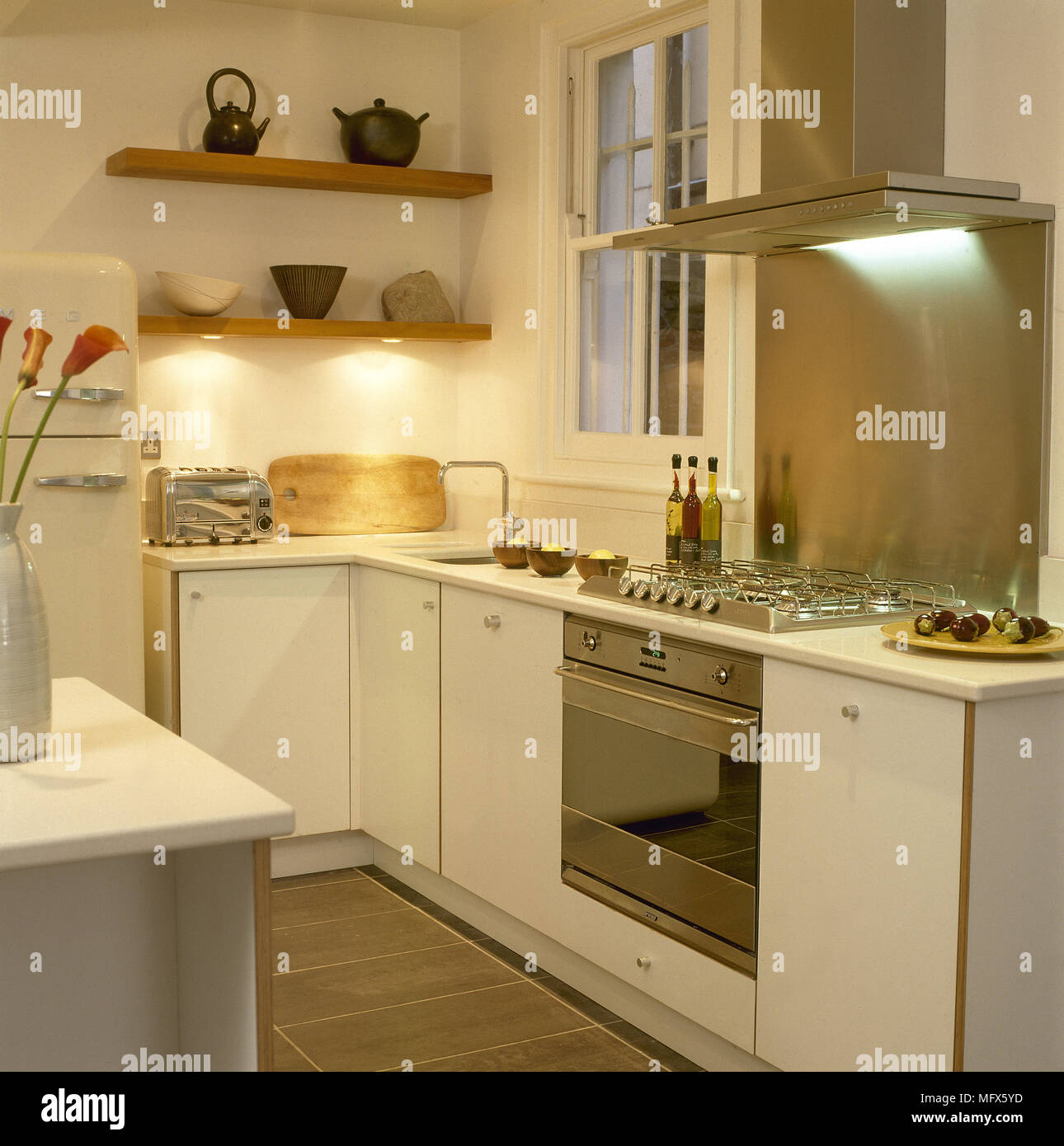 Modern kitchen with a tiled floor, open shelving, white cabinets, and a ...