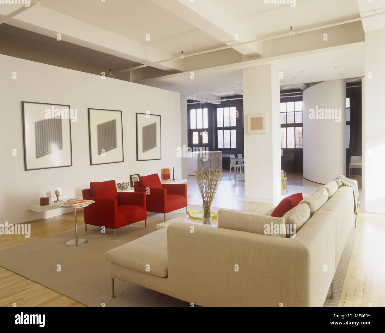 A modern minimalist open plan sitting room with red armchairs neutral ...