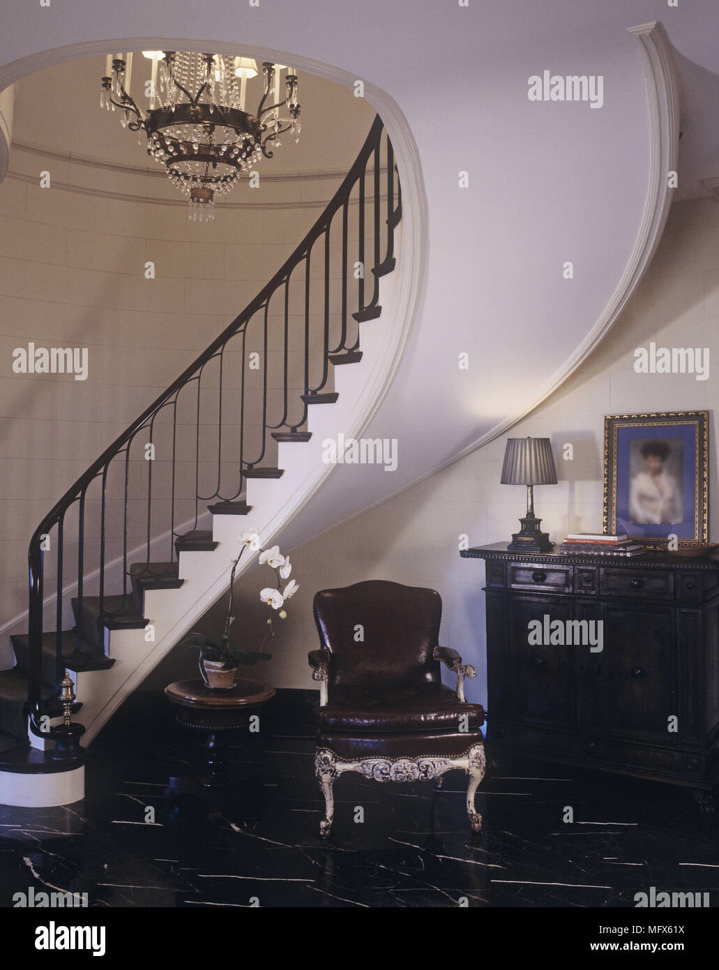 A traditional hallway a sweeping staircase glass chandelier cabinet and ...