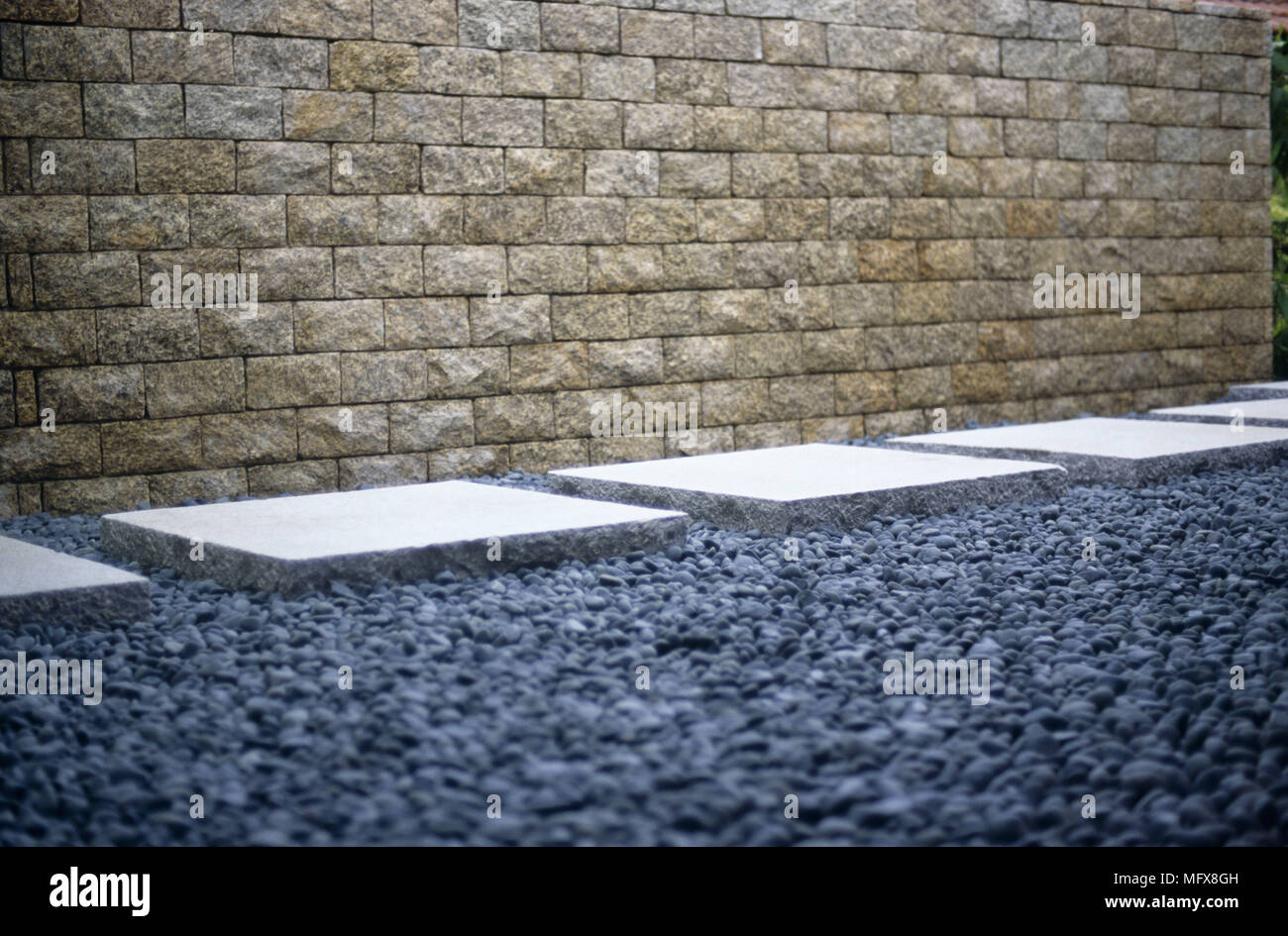 Stone paving slabs set in gravel against brick stone wall Stock Photo ...