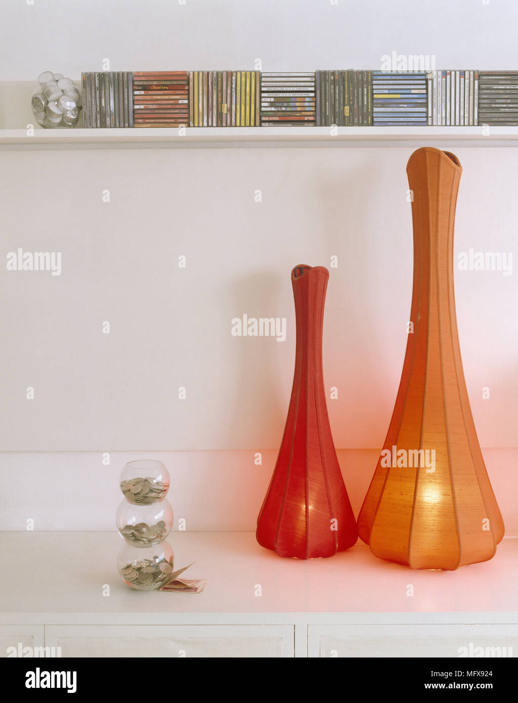 Decorative tiles on shelf above two glowing orange lamps on sideboard ...