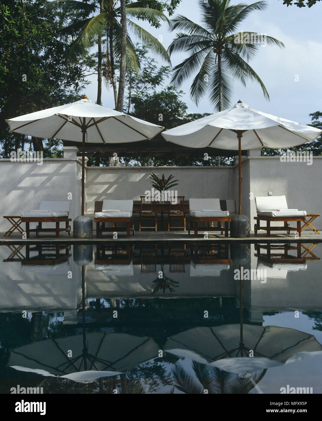 Sun loungers and parasols beside swimming pool Stock Photo - Alamy