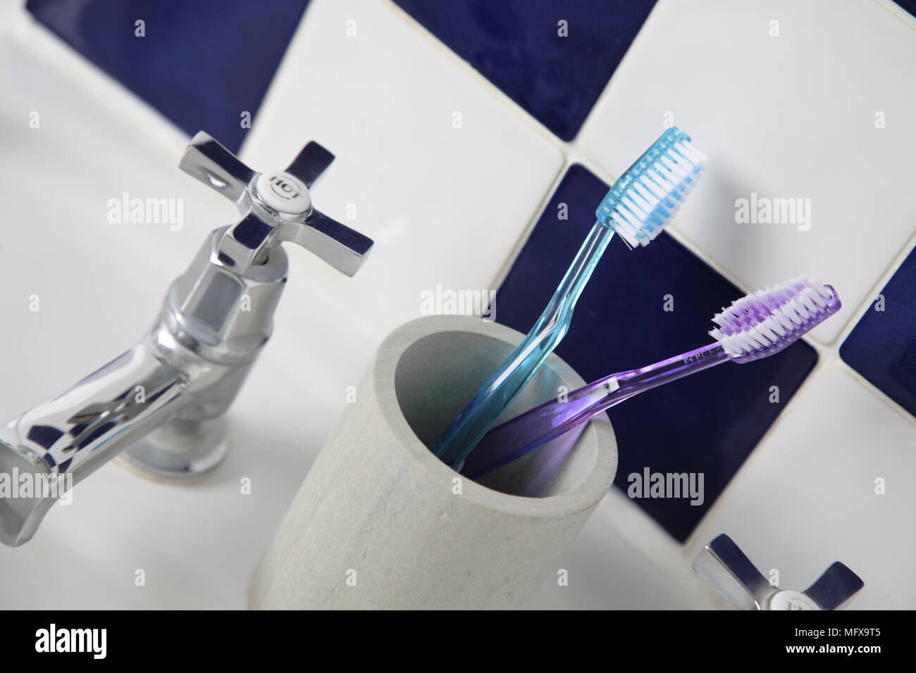 Toothbrushes in a holder on a sink and tiled black and white wall Stock ...