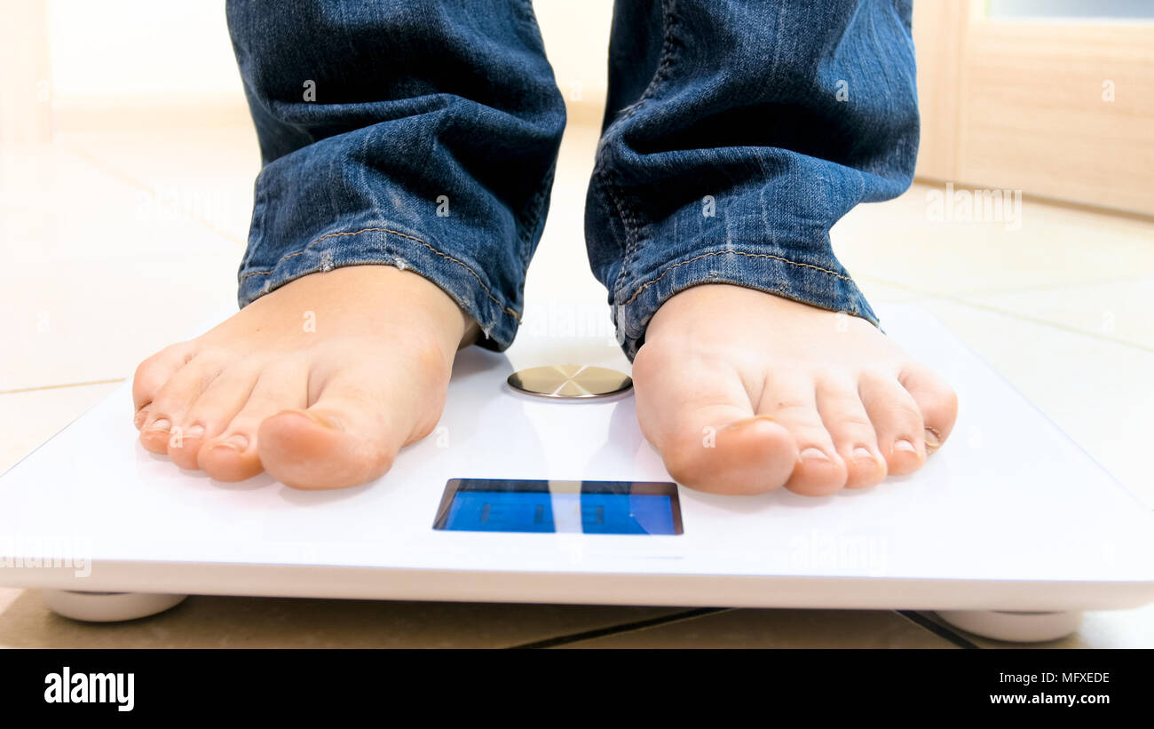 Young woman in jeans weighting herself on scales Stock Photo - Alamy