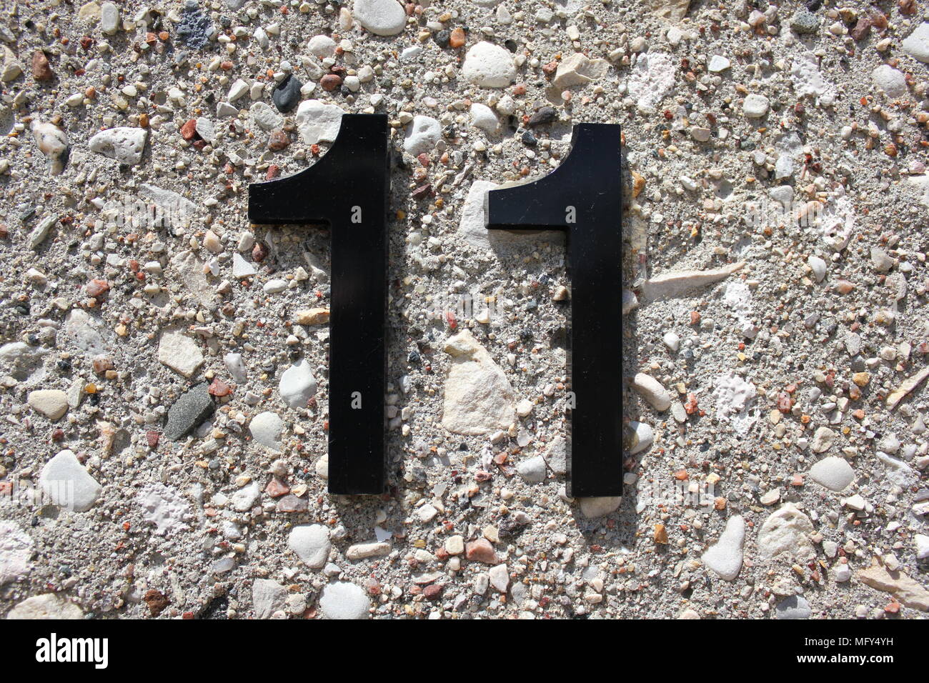 The number eleven as a black plastic text glued to a textured pebble ...