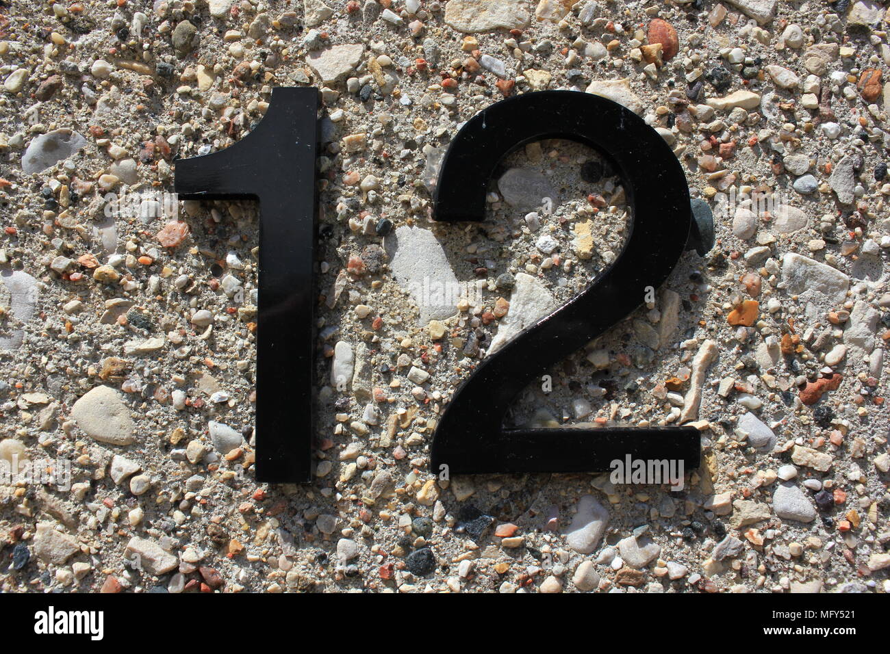 The number twelve as a black plastic text on a textured pebble ...