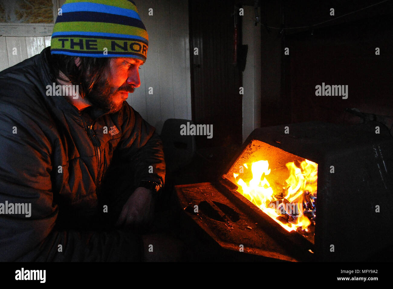 A man lights the wood burner at Coire Fionnaraich Bothy near Coulags ...