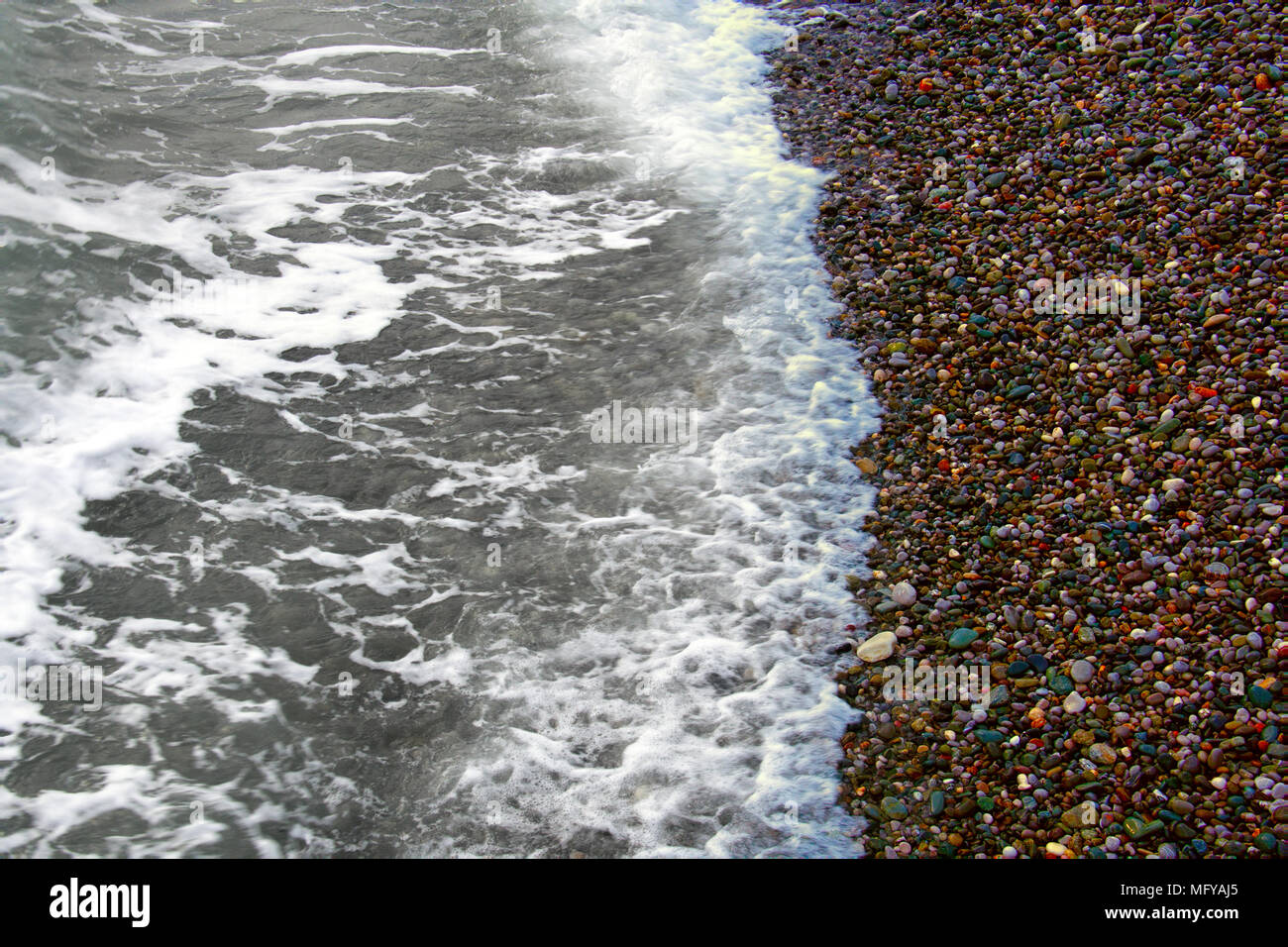 Beach of multi-colored round pebbles, and the splash of salty waves ...