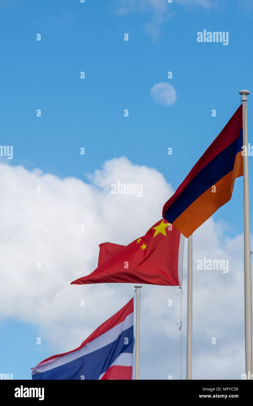 international flags flying with blue sky and day time moon in ...