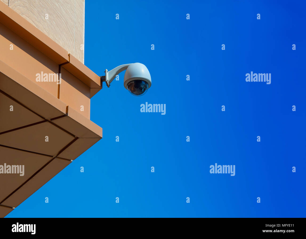video surveilance camera on a building with clear blue sky background ...