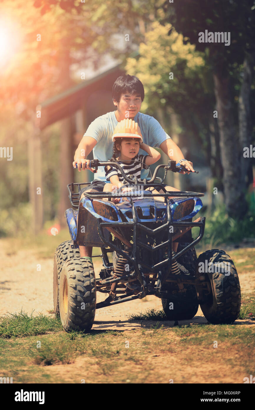 father and daughter riding on quad atv on dirt field Stock Photo - Alamy