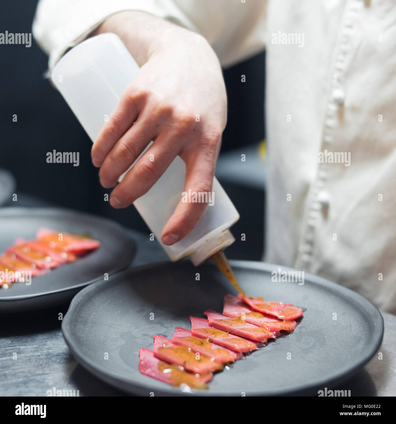 Restaurant Chef cook preparing tuna striped filet and pouring fish with ...