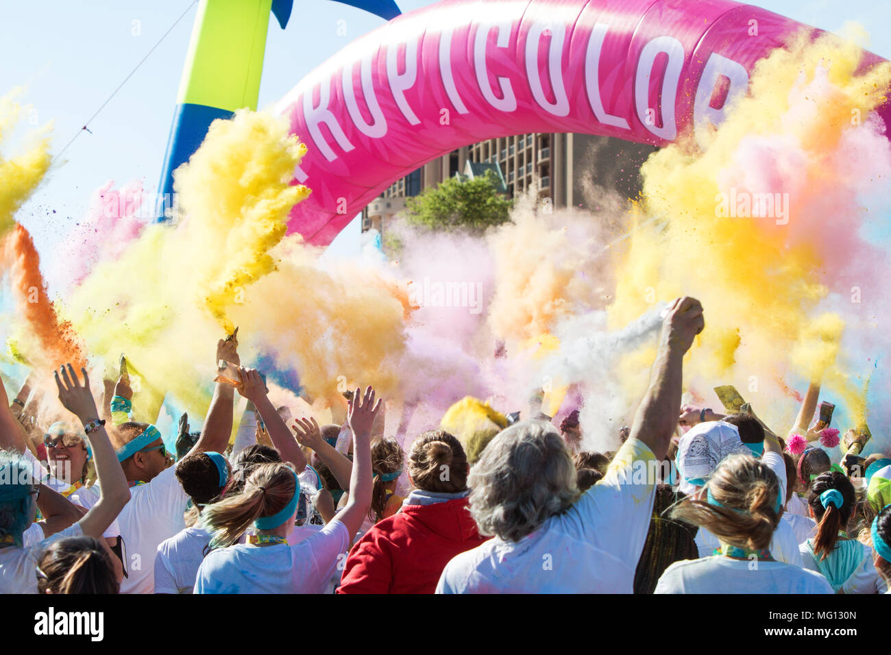 A crowd of runners who completed the Color Run, toss packets of colored ...