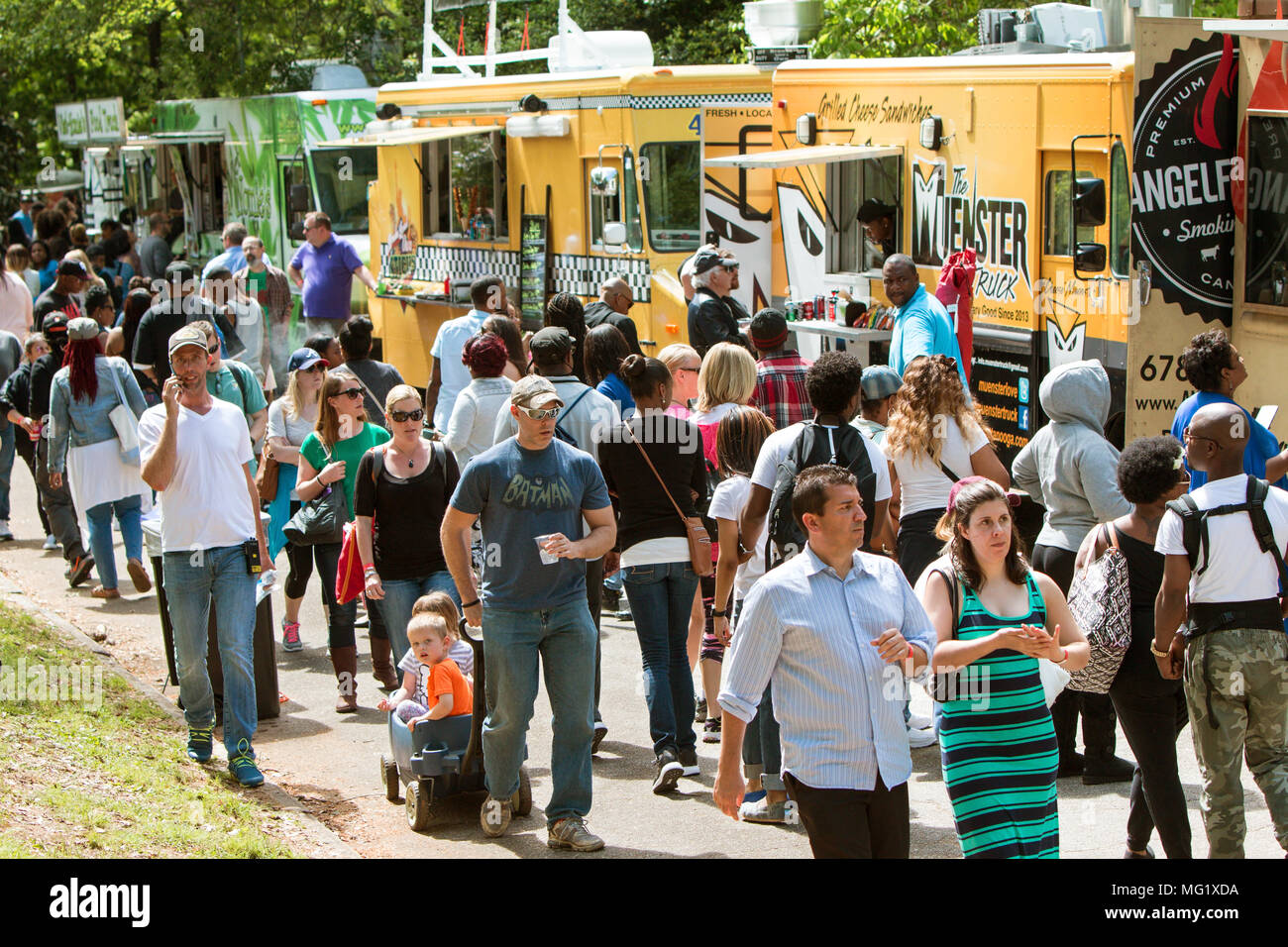 A crowd of people survey their choices and buy meals from food trucks ...