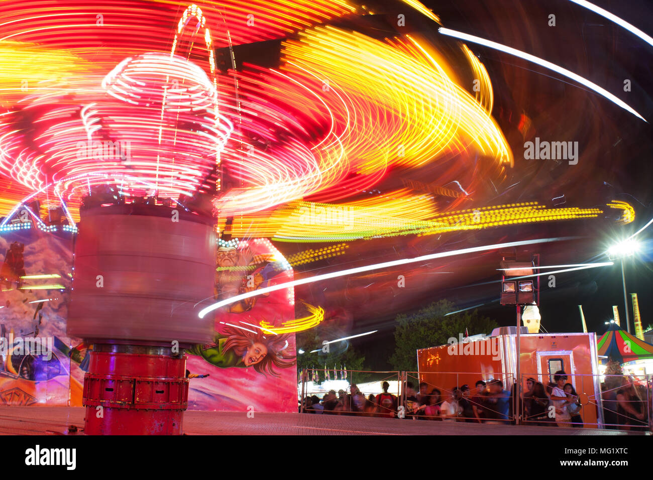 Motion blur shows colorful, streaking lights of fast-moving carnival ...