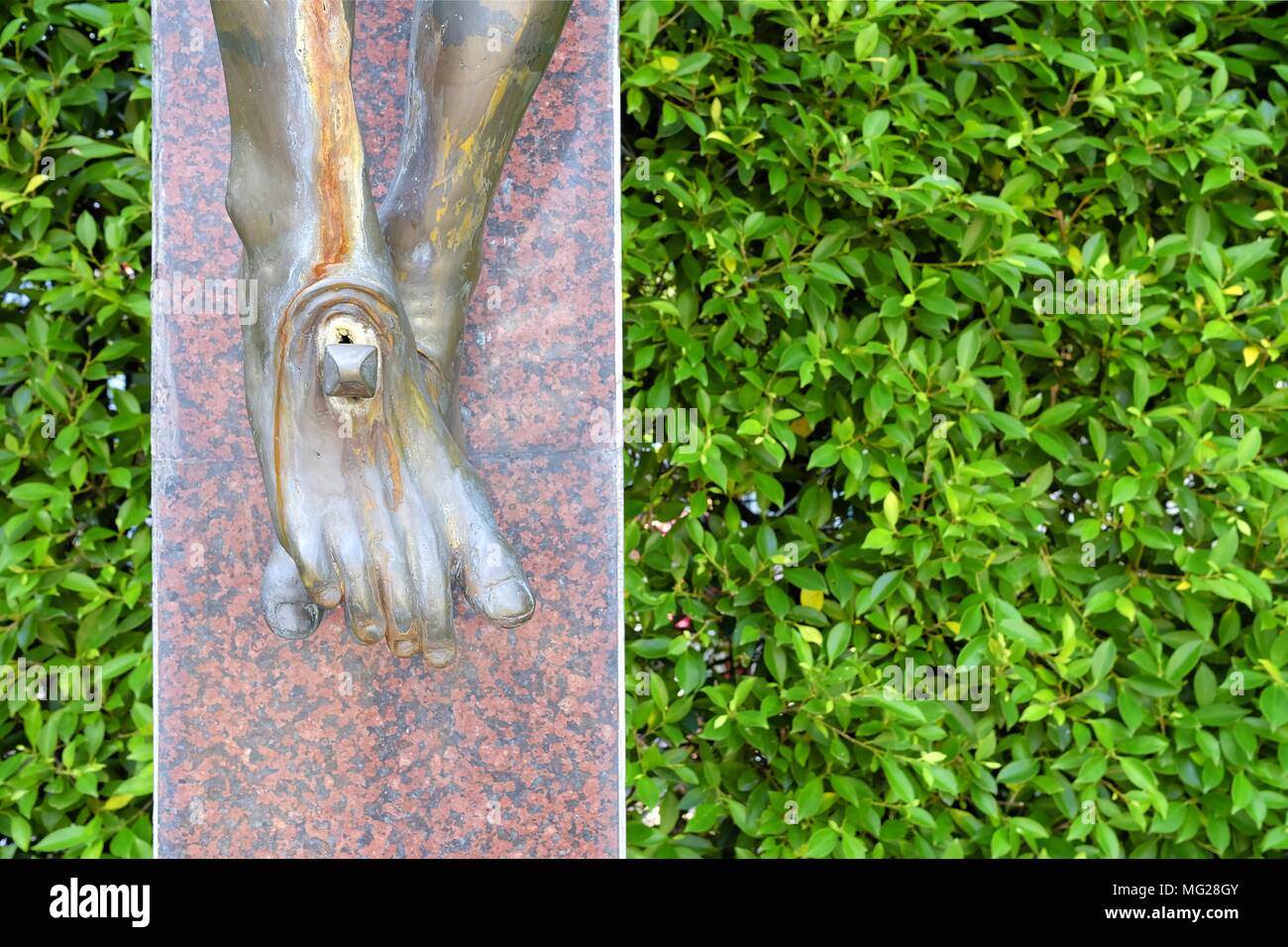 Close-up Legs of Jesus Statue with Green Leaves Wall Background Stock ...