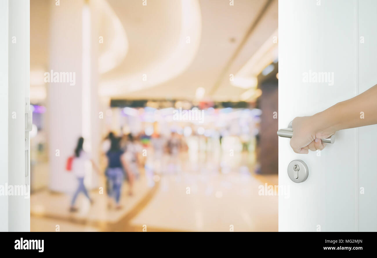 man hand opening white door to department store with people shopping as ...