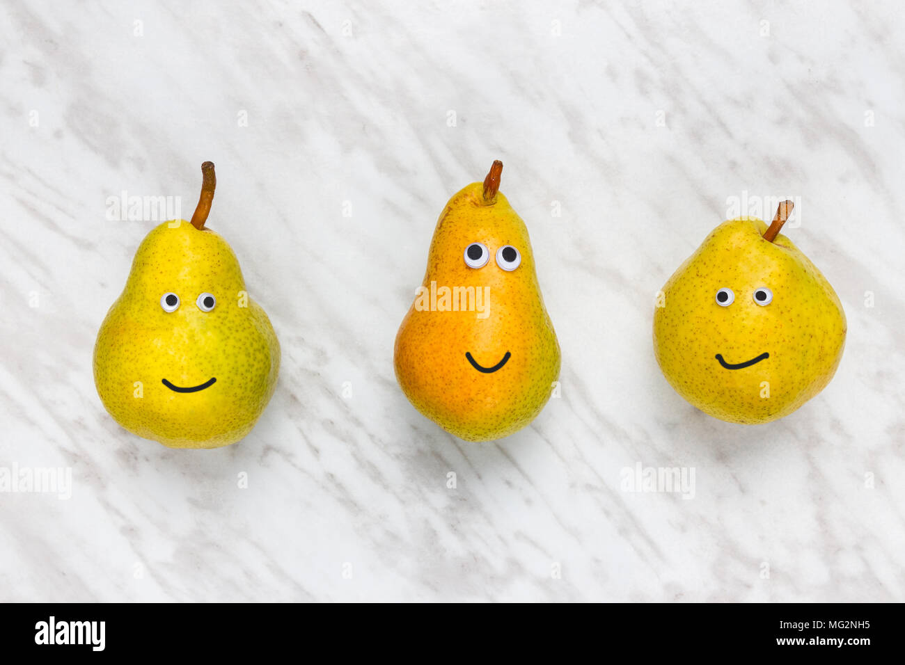 Three funny smiling pears on marble background. Different personalities ...