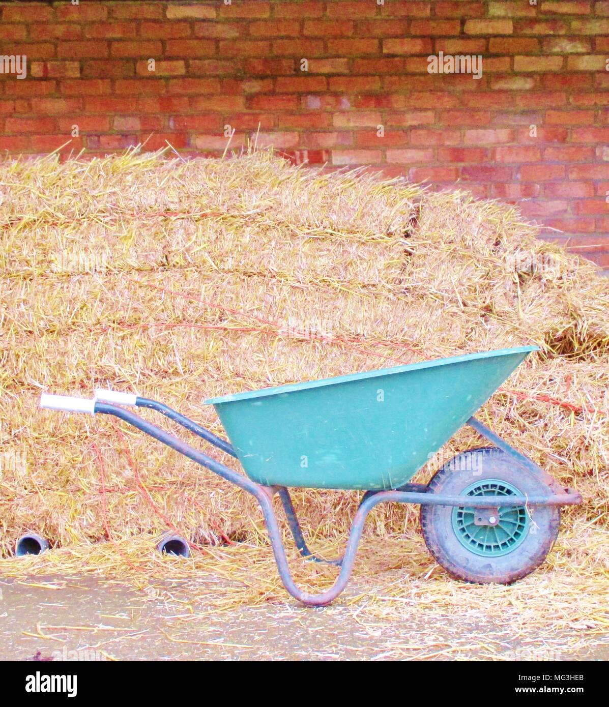 red Brick wall with hay bales and wheel barrow Stock Photo - Alamy