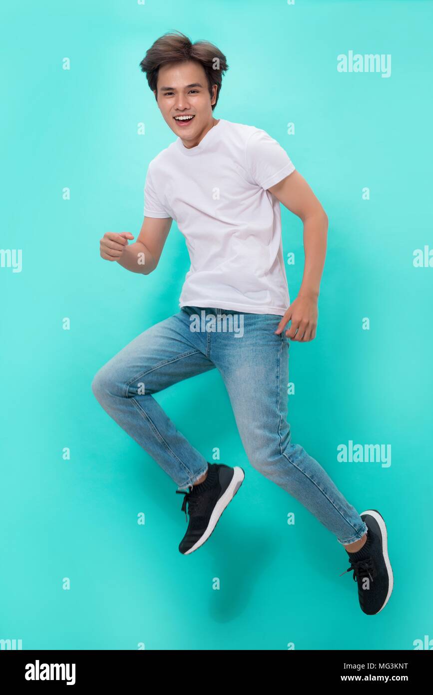 Handsome asian man jumping over blue background Stock Photo - Alamy