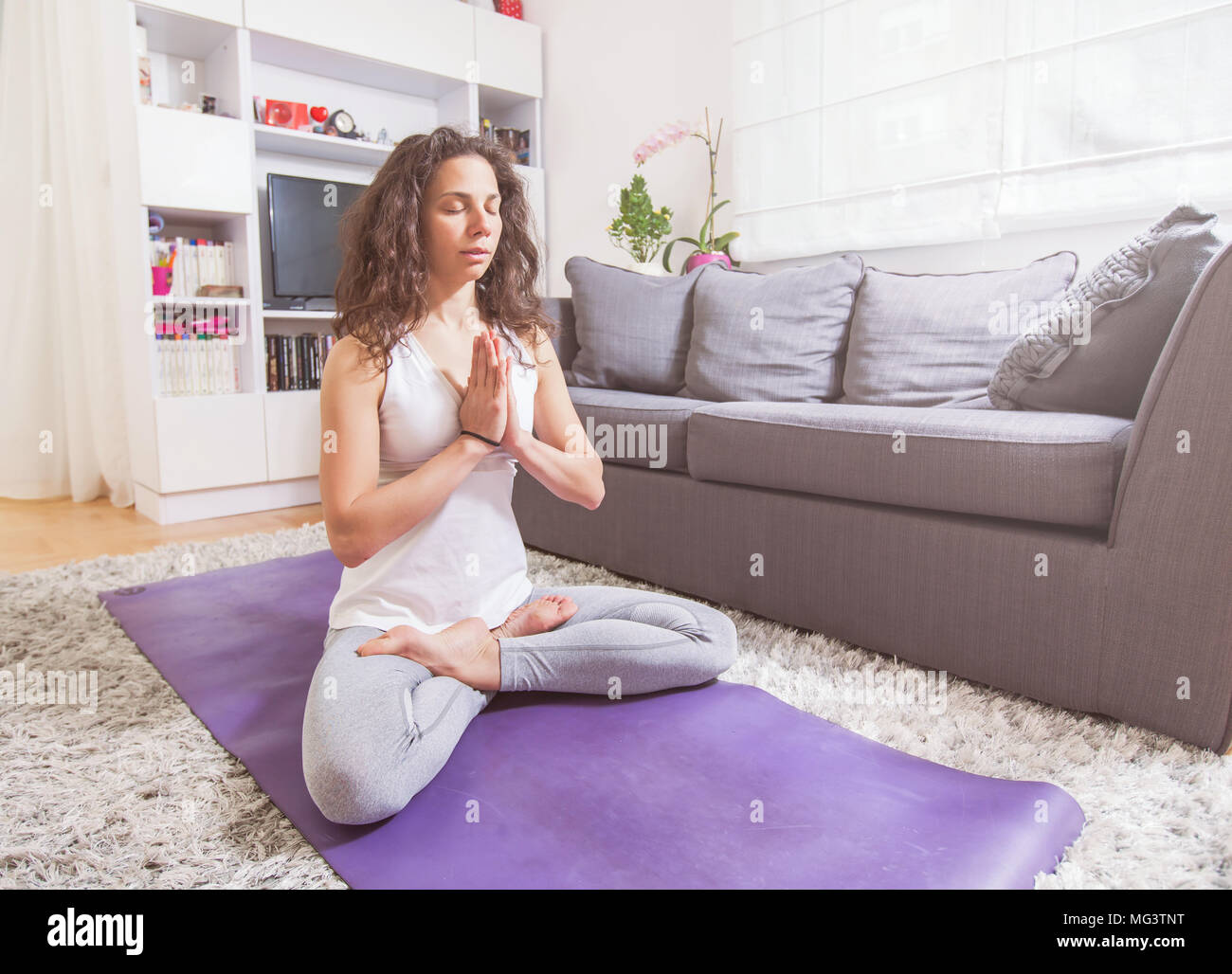 Young Woman Meditating and Practicing Yoga, lotus pose namaste gesture ...