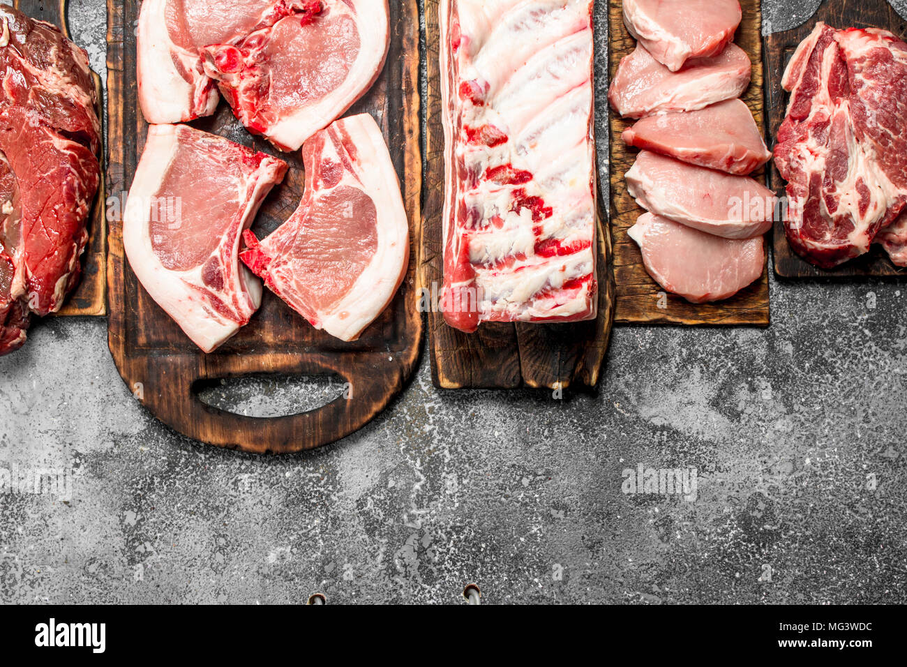 Different types of raw meat on the boards. On rustic background Stock ...
