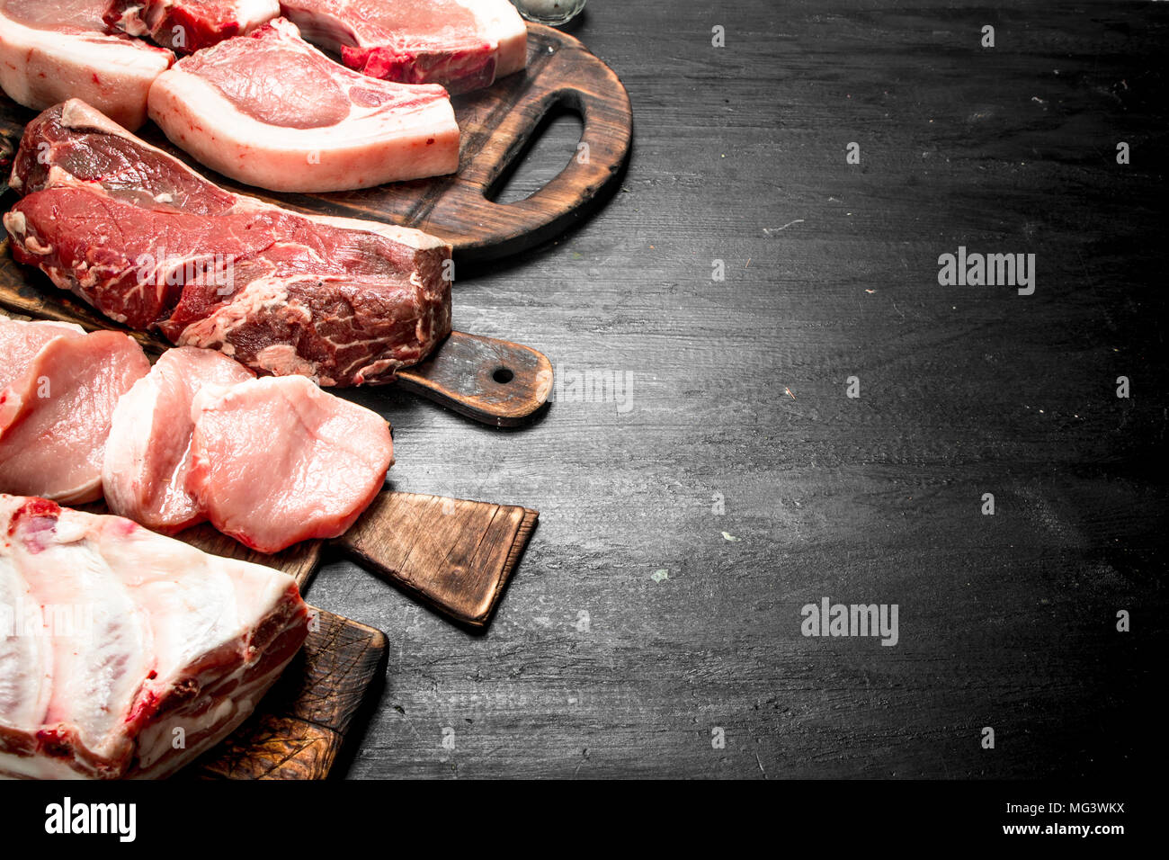 Different types of raw pork meat and beef. On the black chalkboard ...