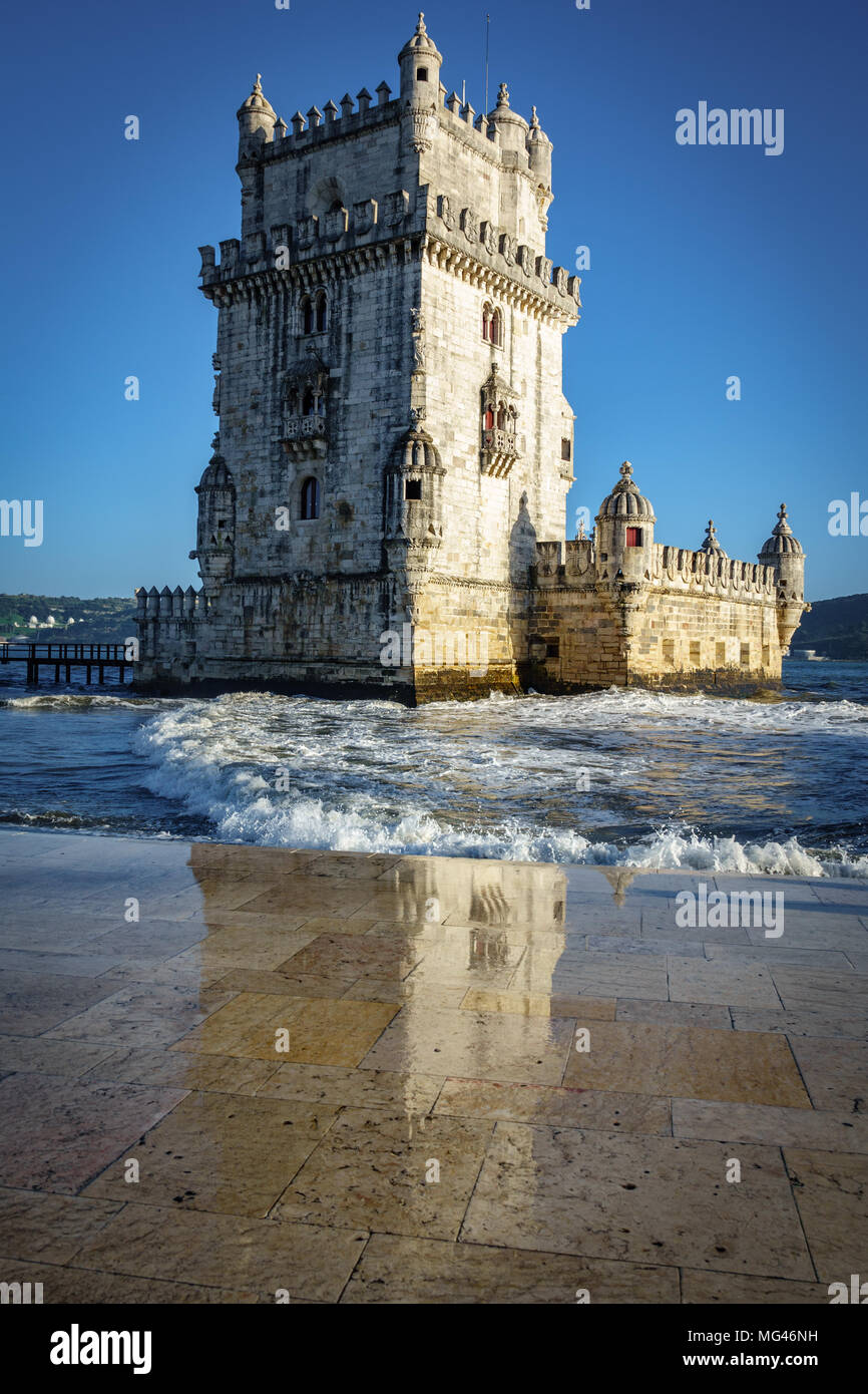 Vertical view of the Belem tower and reflection at the riverside of ...