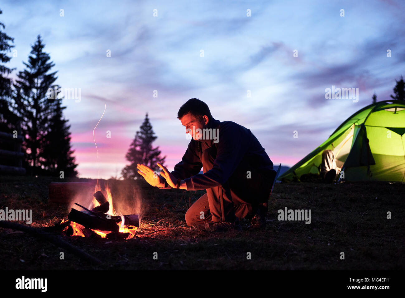 Hiking tourist have a rest in his camp at night near campfire Stock ...
