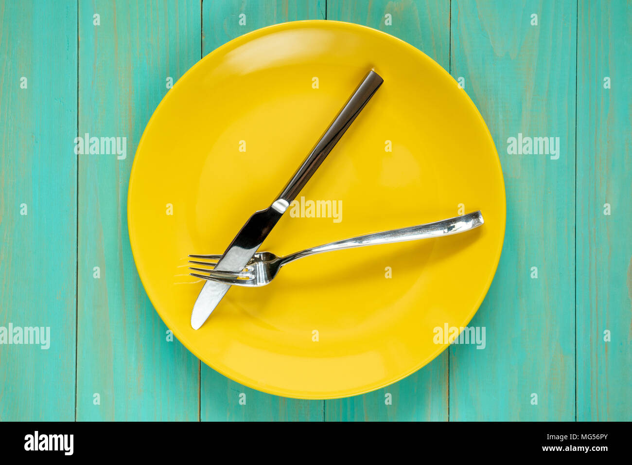 Empty yellow plate with fork and knife Stock Photo - Alamy