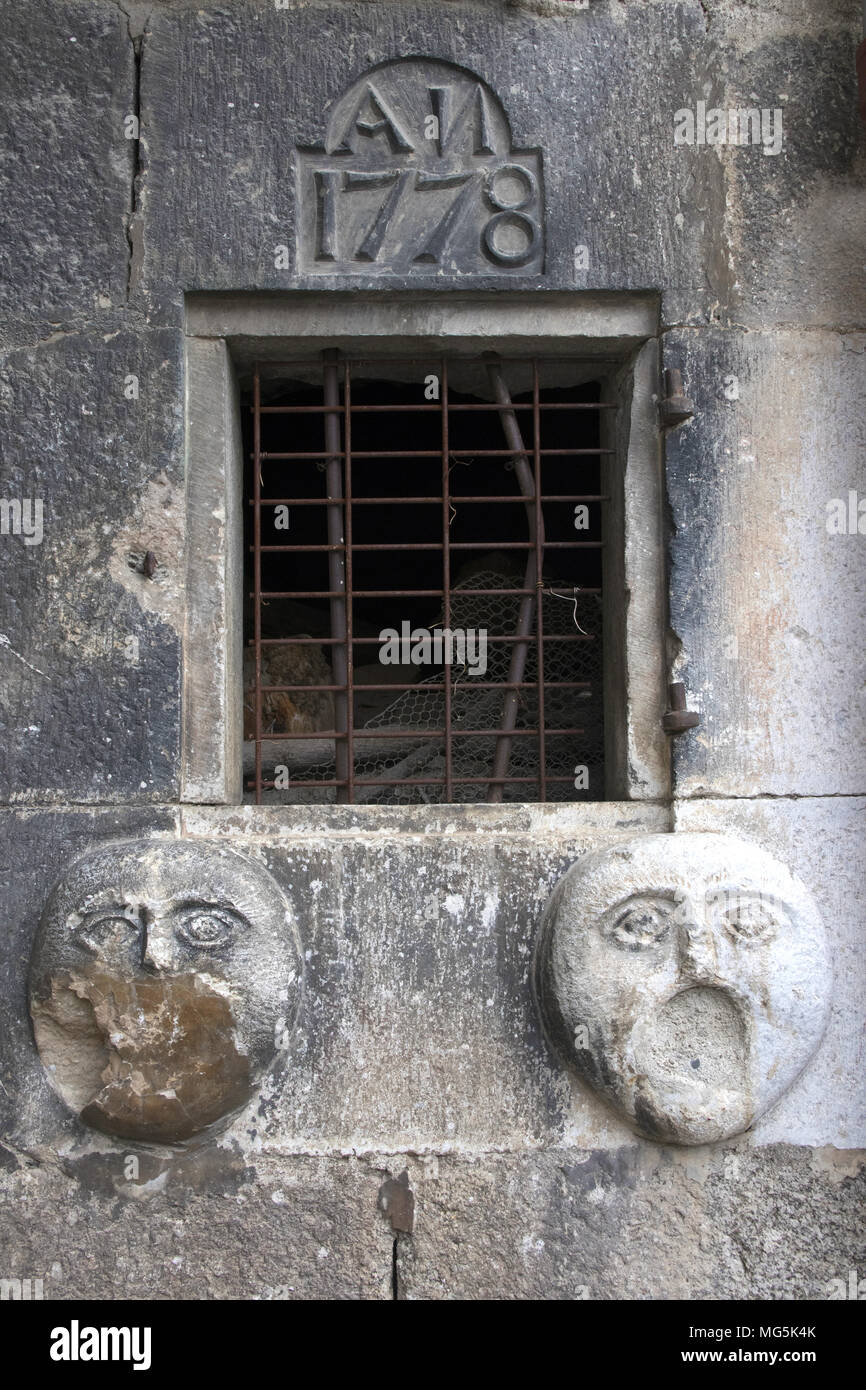 small square window with stone carvings around it, in Mosset, a small ...