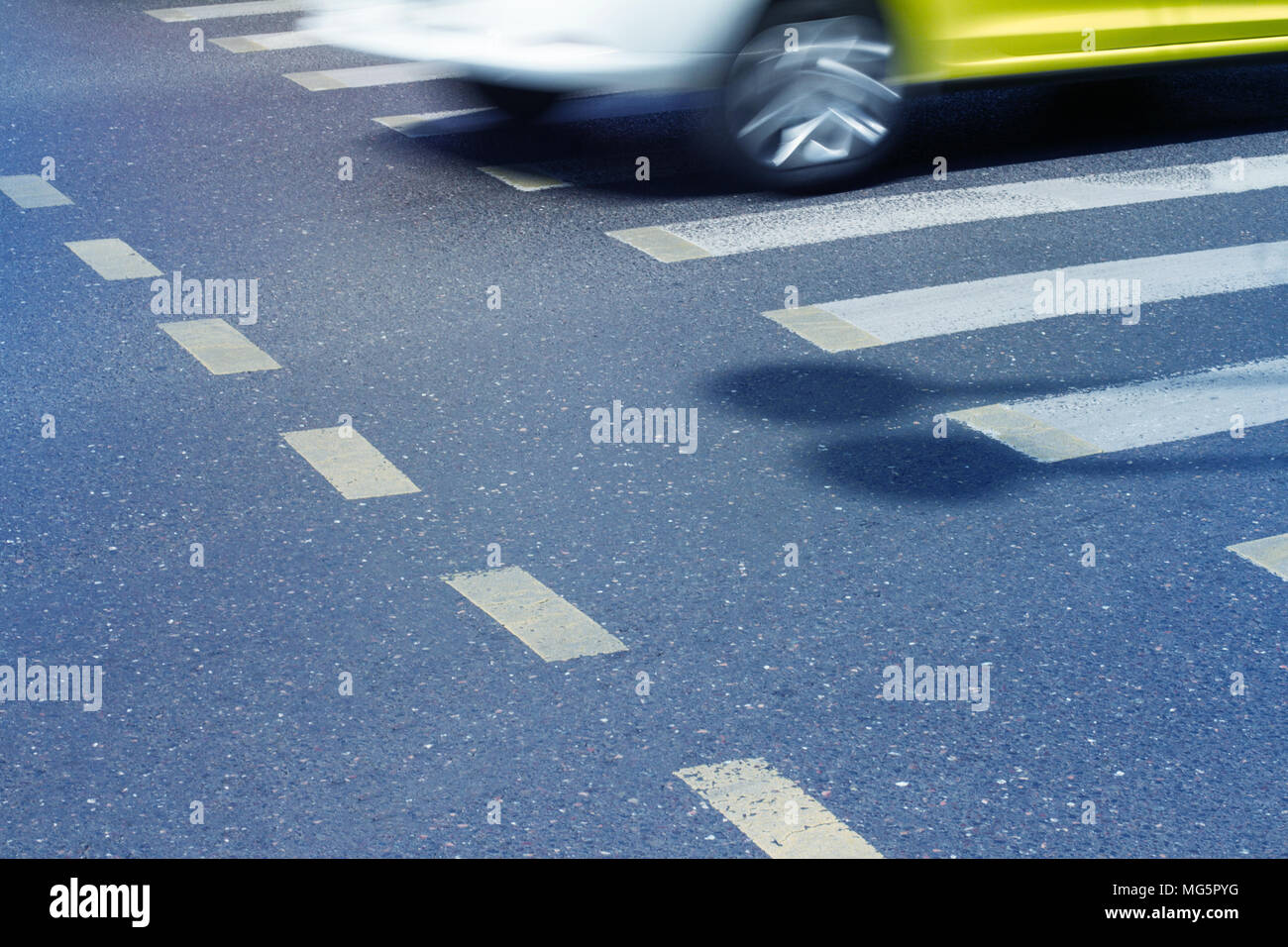 horizontal closeup of yellow car with motion blur near a pedestrian ...