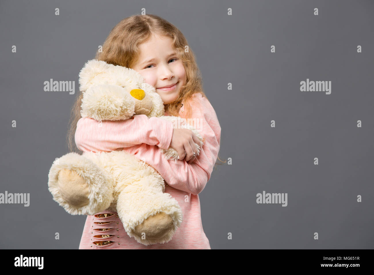 Delighted nice girl hugging her toy Stock Photo - Alamy
