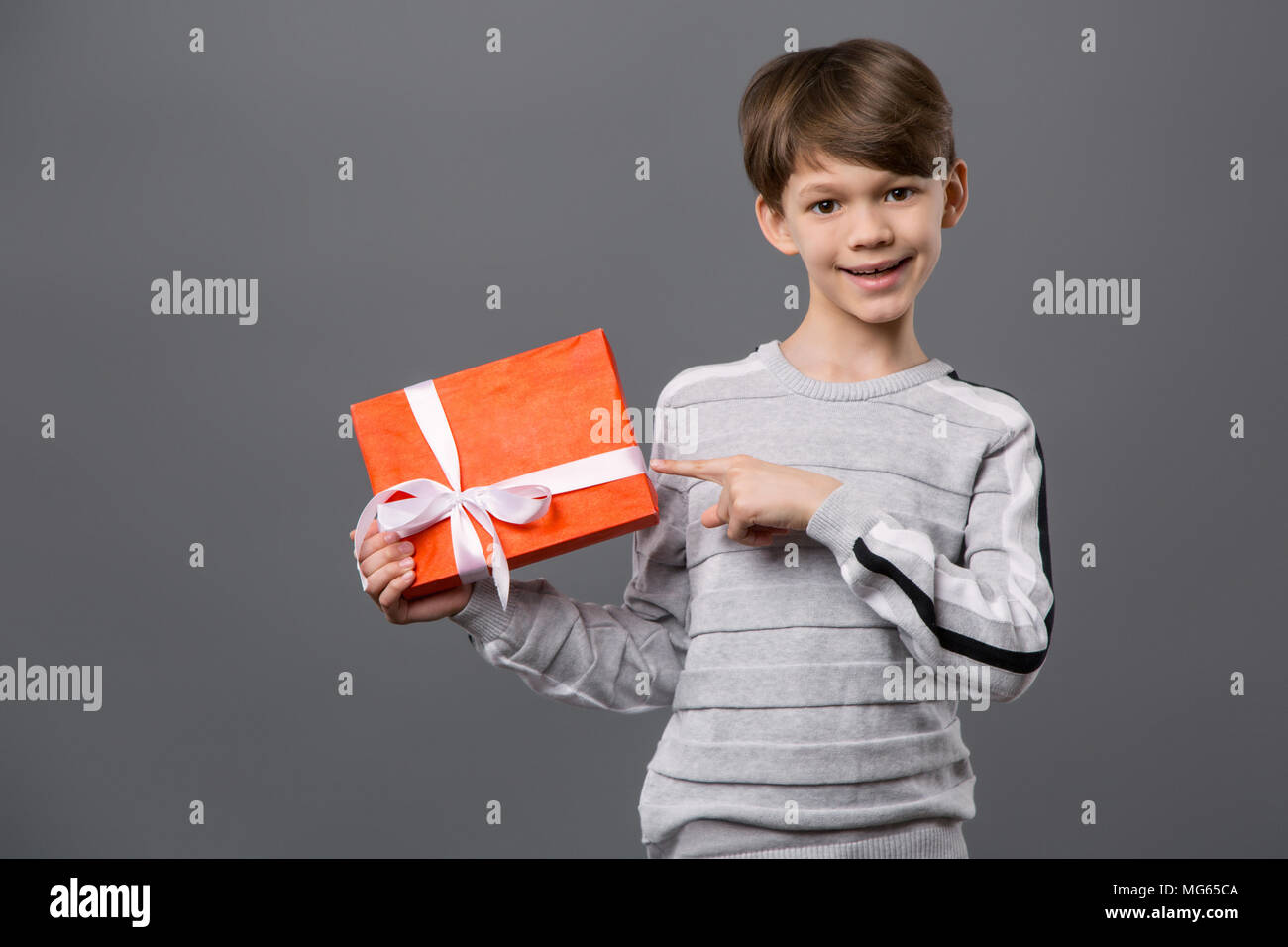 Positive cute boy pointing at the gift box Stock Photo - Alamy