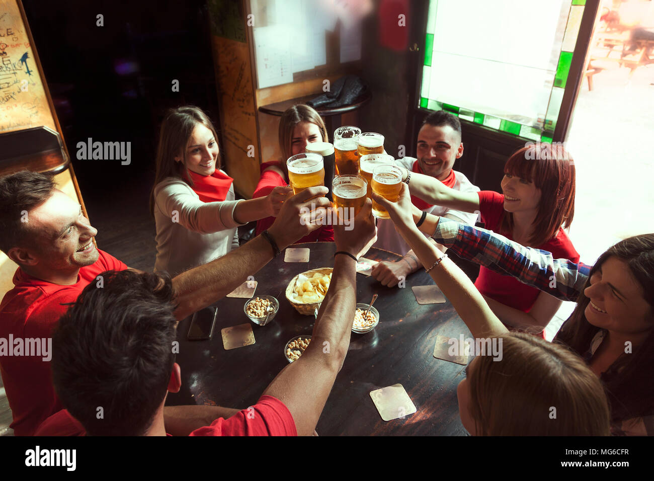 group of people celebrating in a pub drinking beer and eating snacks ...