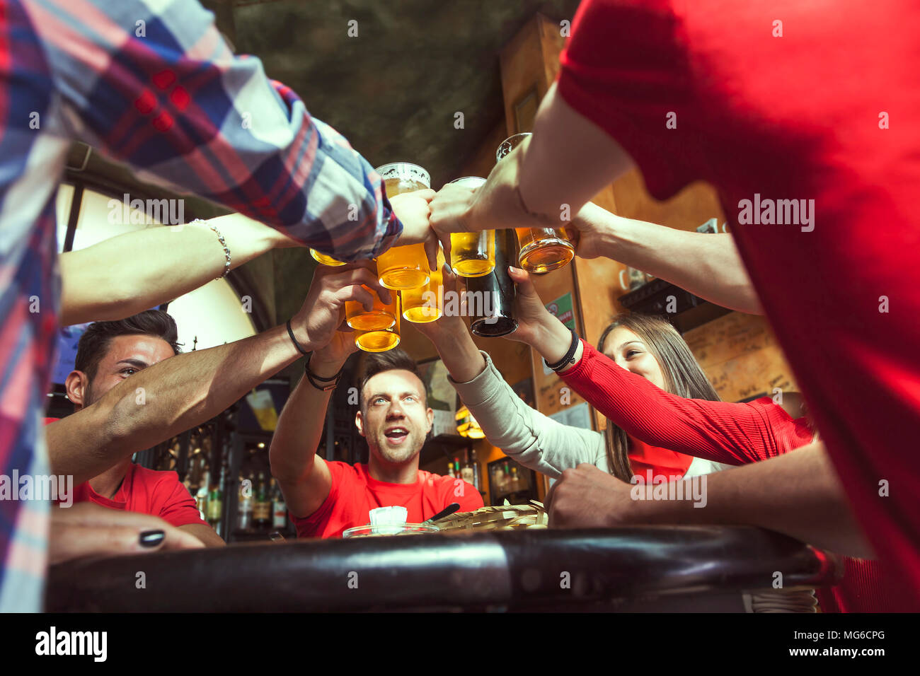 group of people celebrating in a pub drinking beer and eating snacks ...