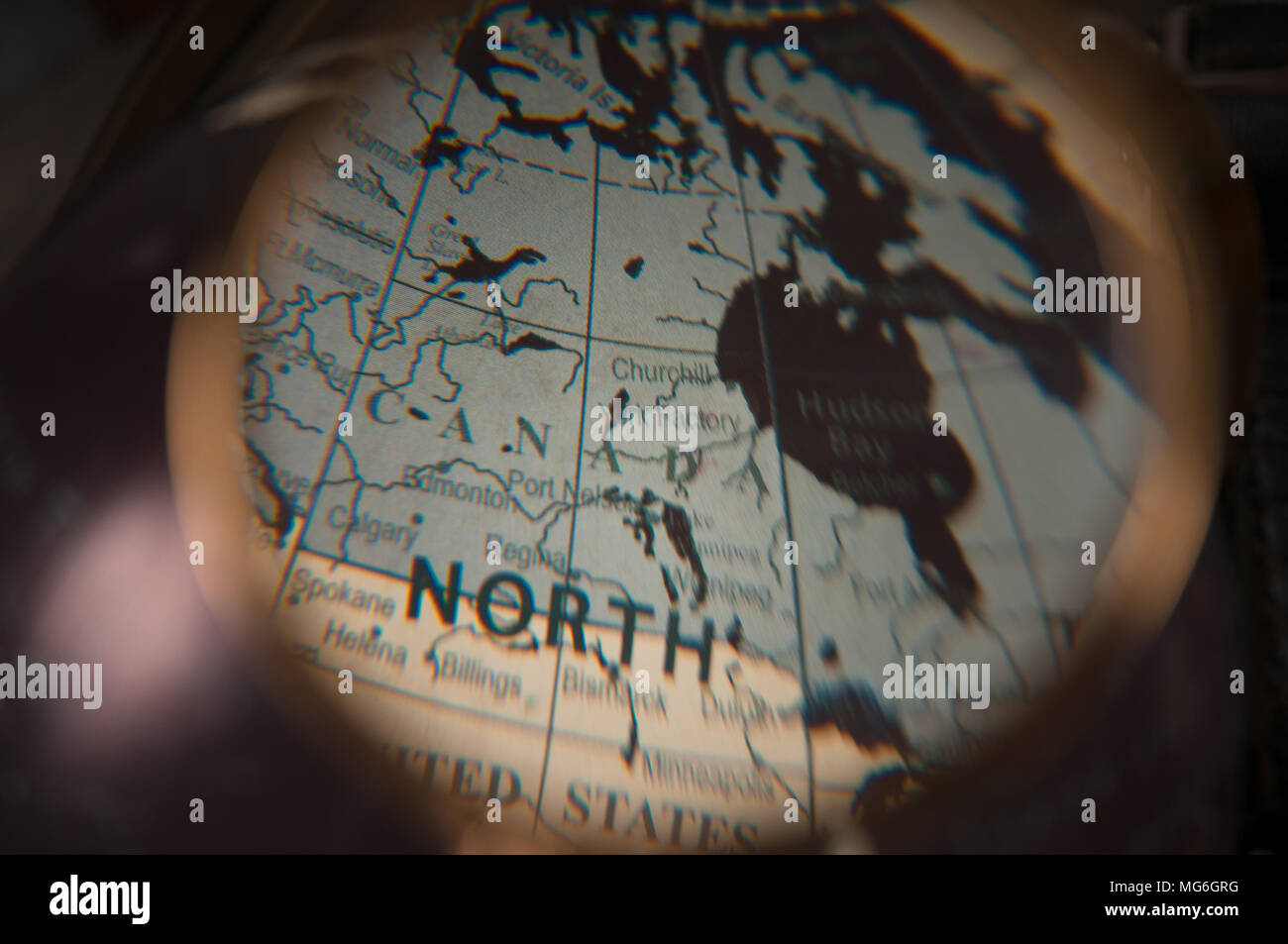 Focus on Canada world map under magnifying glass Stock Photo - Alamy