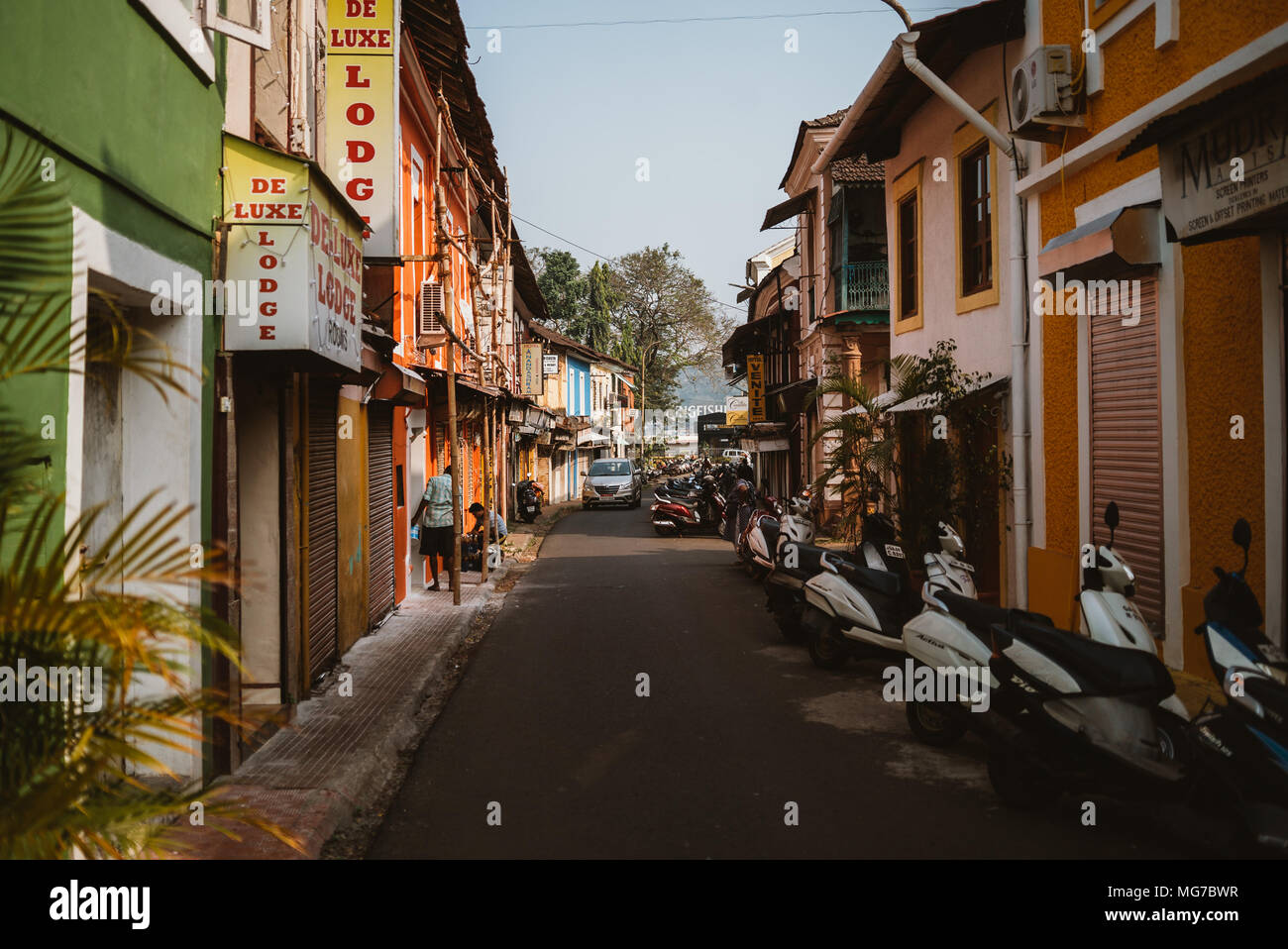 narrow colorful street lines with scooters on a sunny day in Goa, India ...