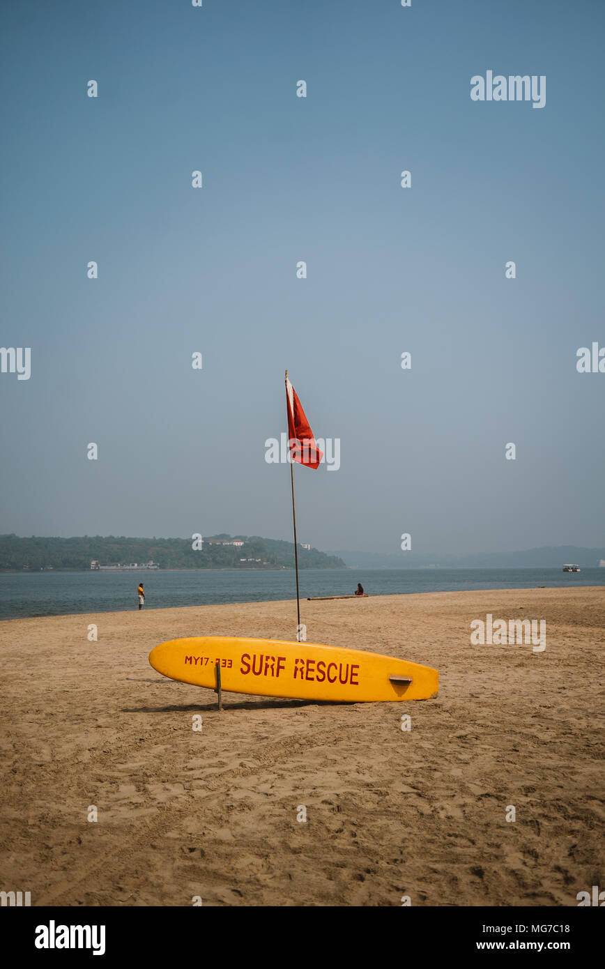 a yellow surfboard and a red flag on a beach in Goa, India Stock Photo ...